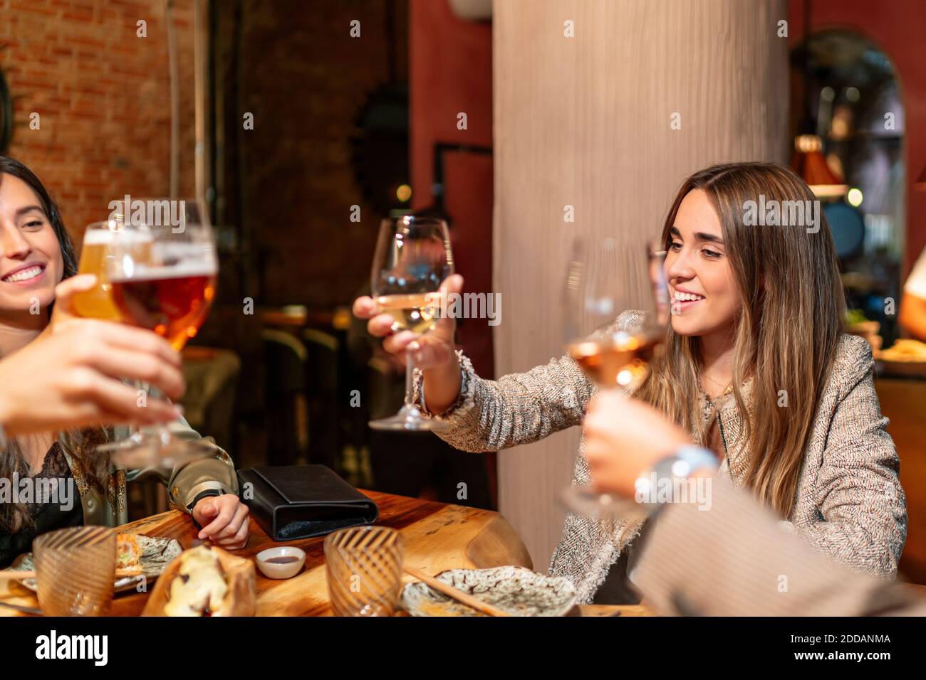 Friends toasting drink while sitting by table at restaurant Stock Photo ...