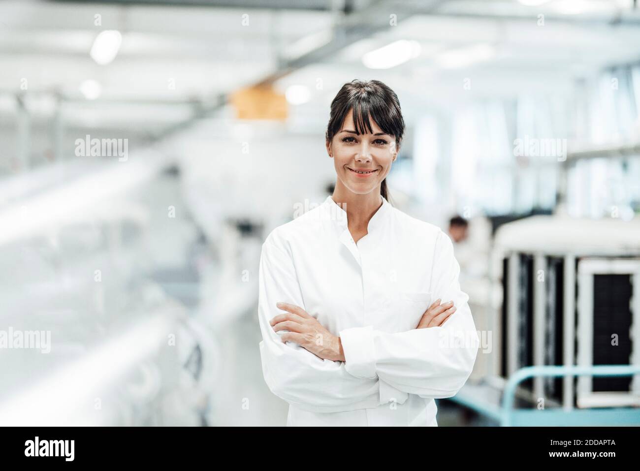 Smiling female scientist standing with arms crossed in bright laboratory Stock Photo - Alamy