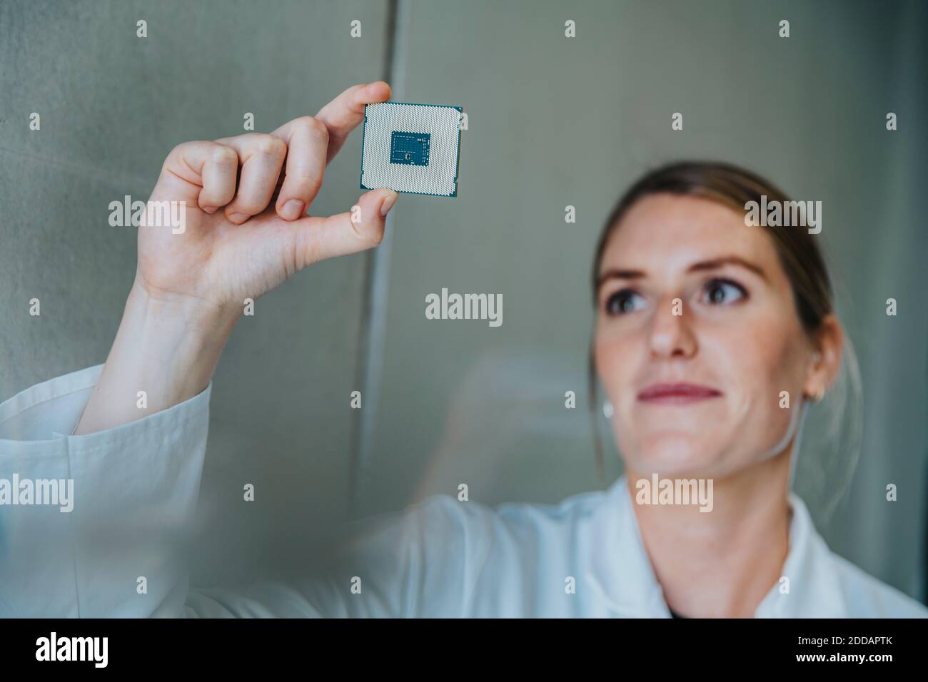 Scientist holding computer chip while standing against wall at clinic ...