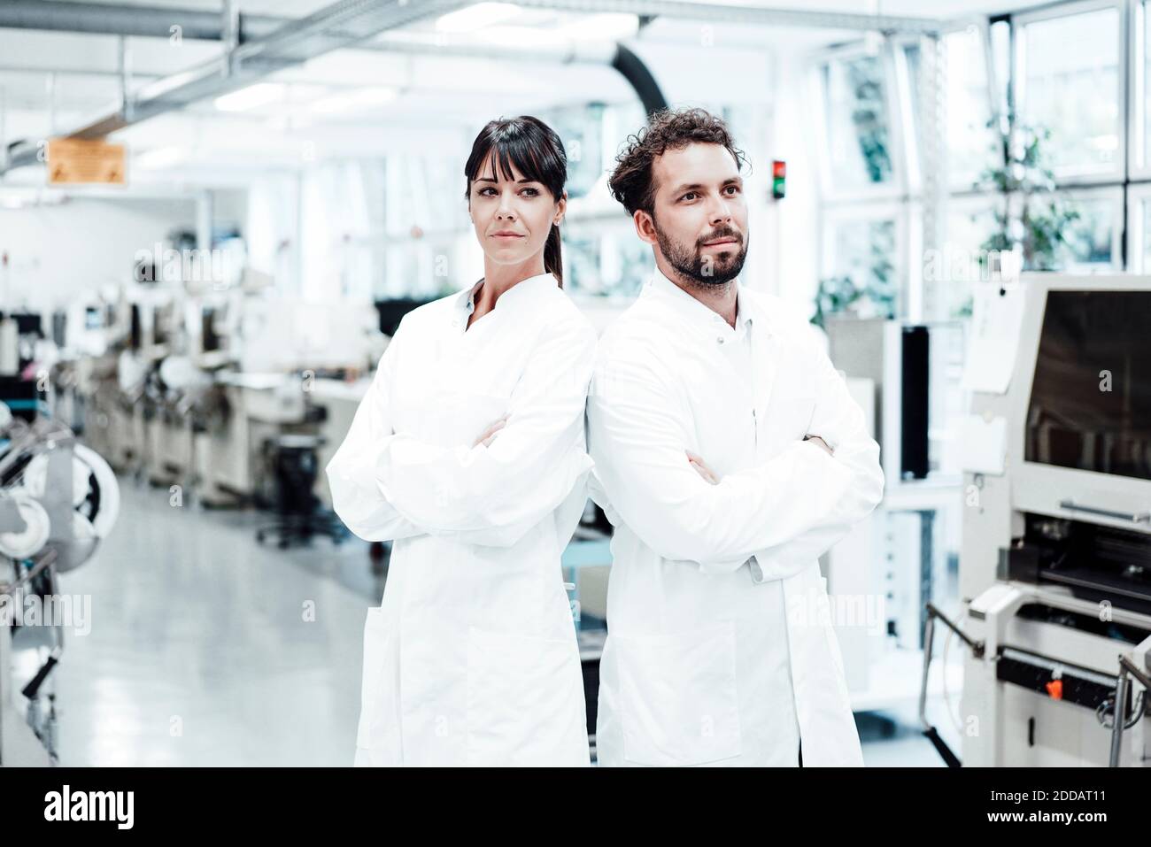 Confident female and male scientists standing with arms crossed at ...