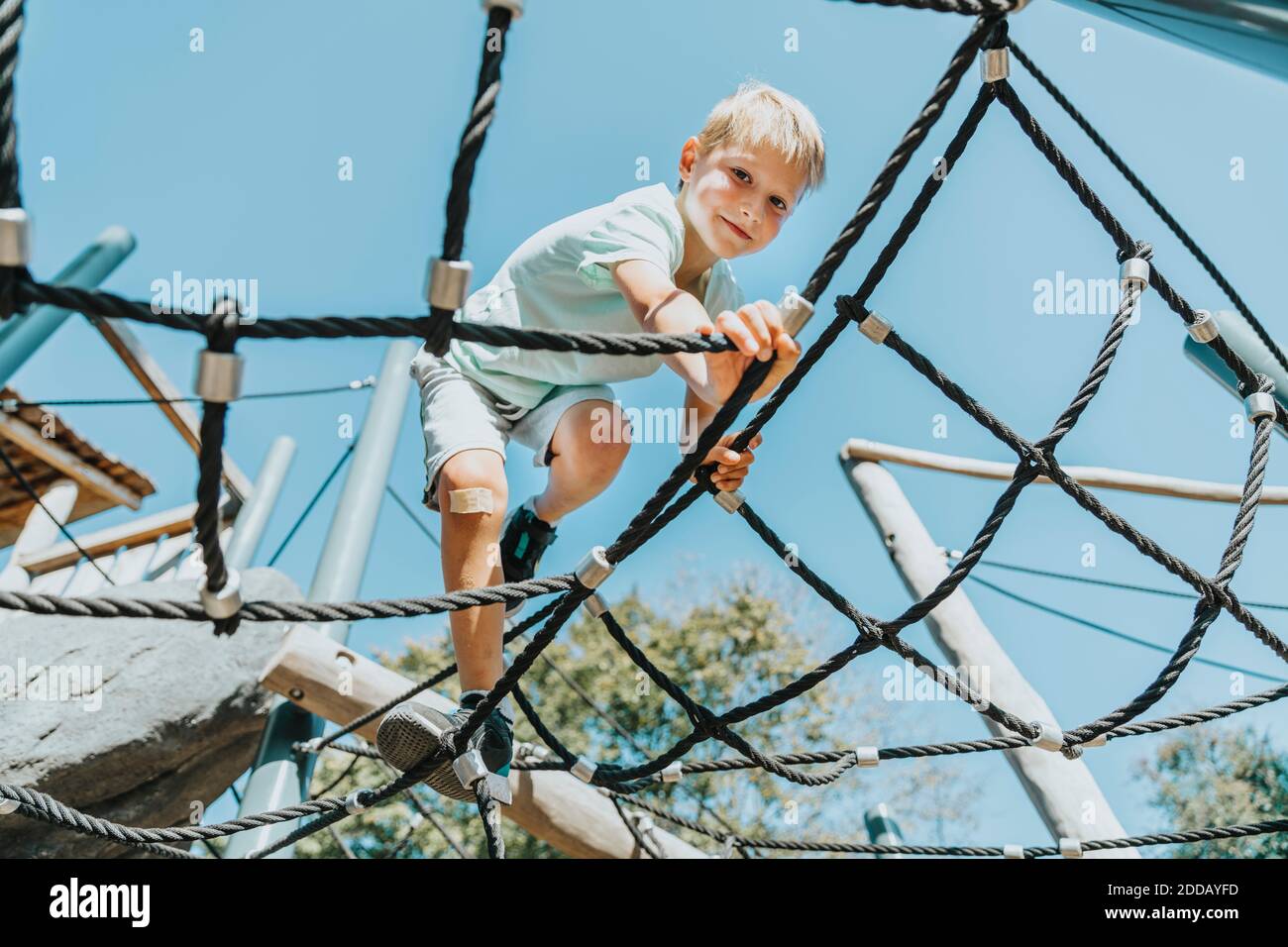 Boy climbing on spider web in public park during sunny day Stock Photo ...