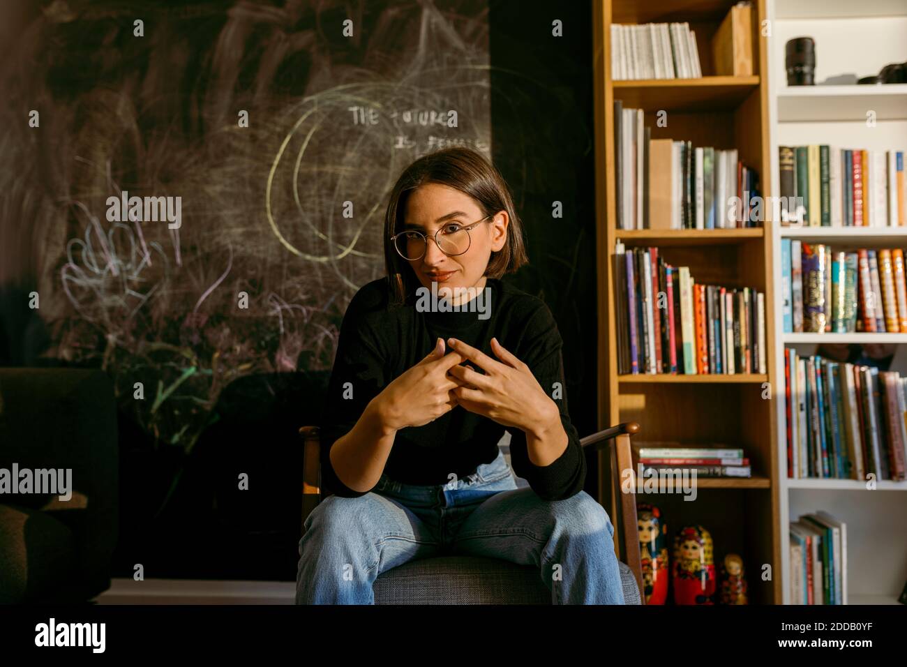 Contemplating woman sitting on chair at home Stock Photo - Alamy