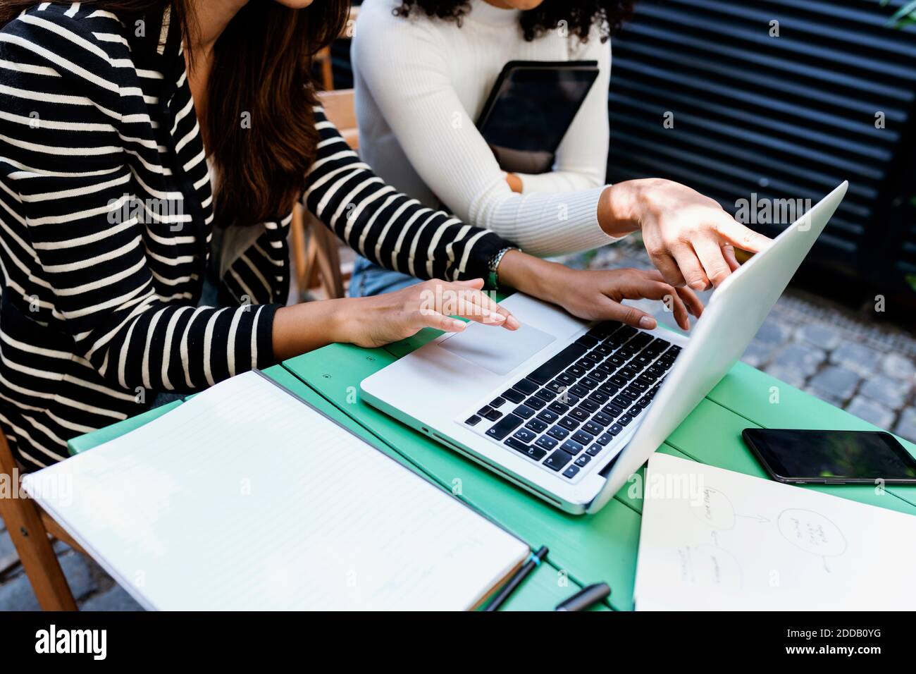 Female colleagues using laptop while sitting on table in cafe Stock ...