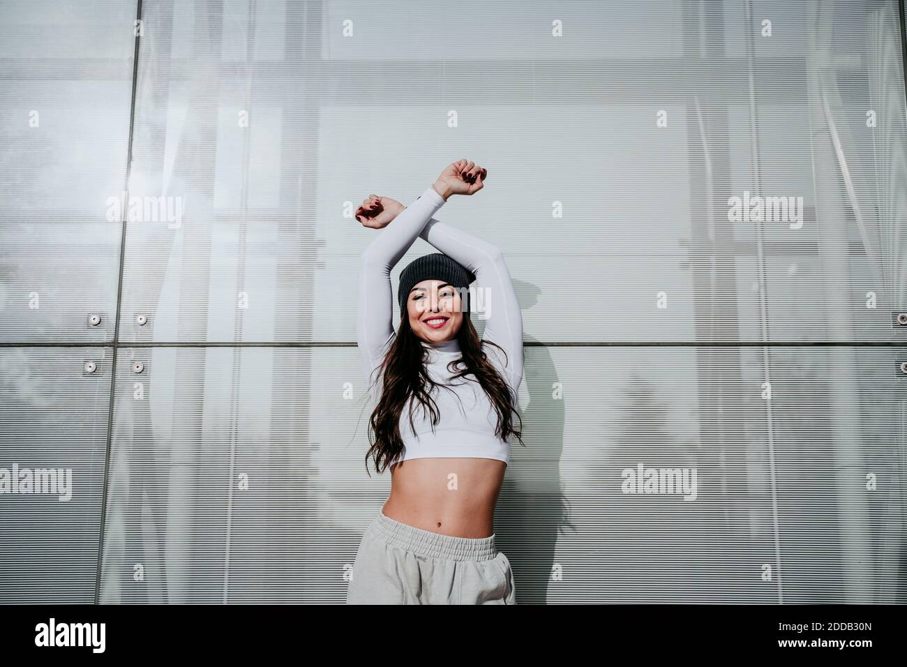 Smiling woman with hands raised standing against wall Stock Photo - Alamy