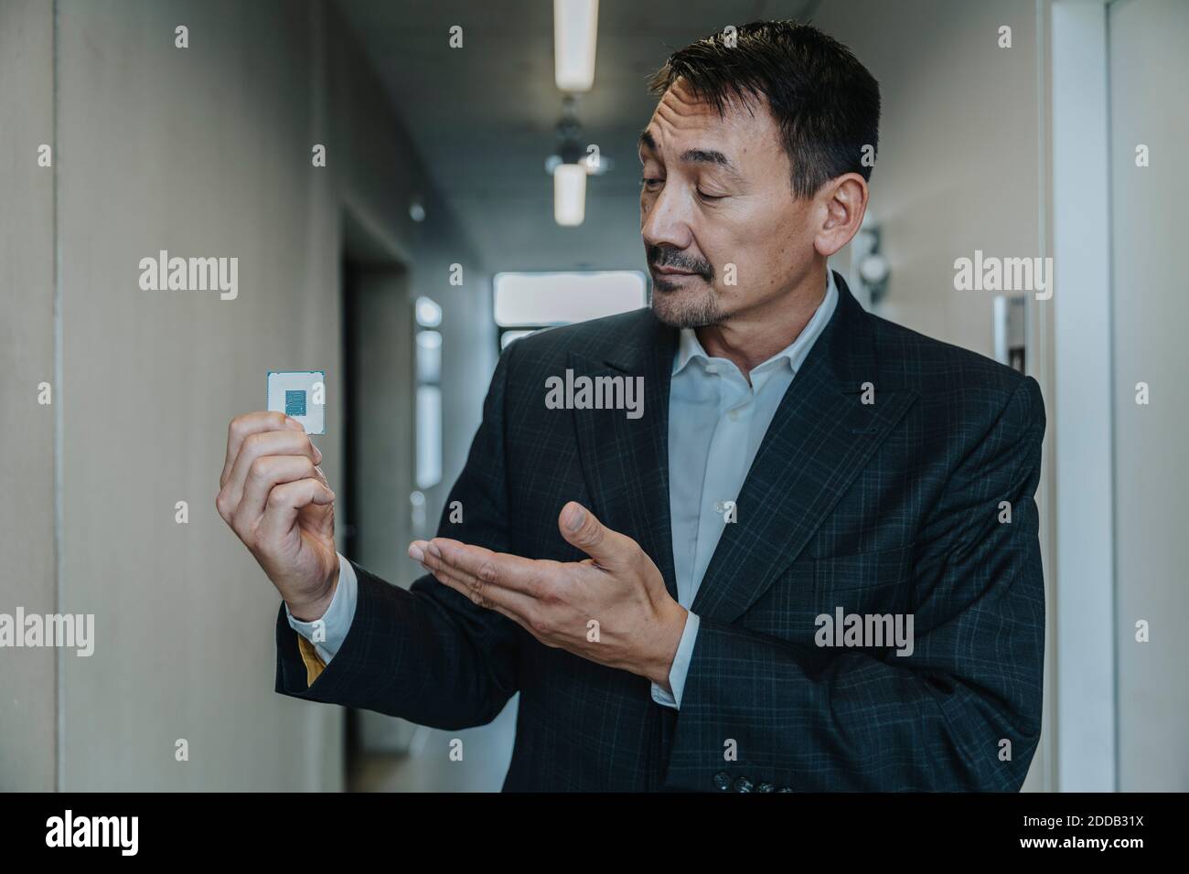 Business man showing computer chip while standing at clinic corridor ...