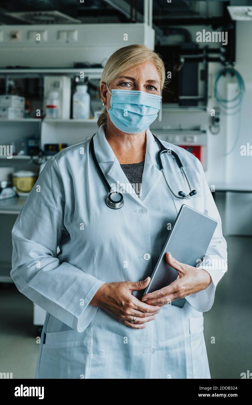 Scientist with face mask and digital tablet standing at laboratory ...
