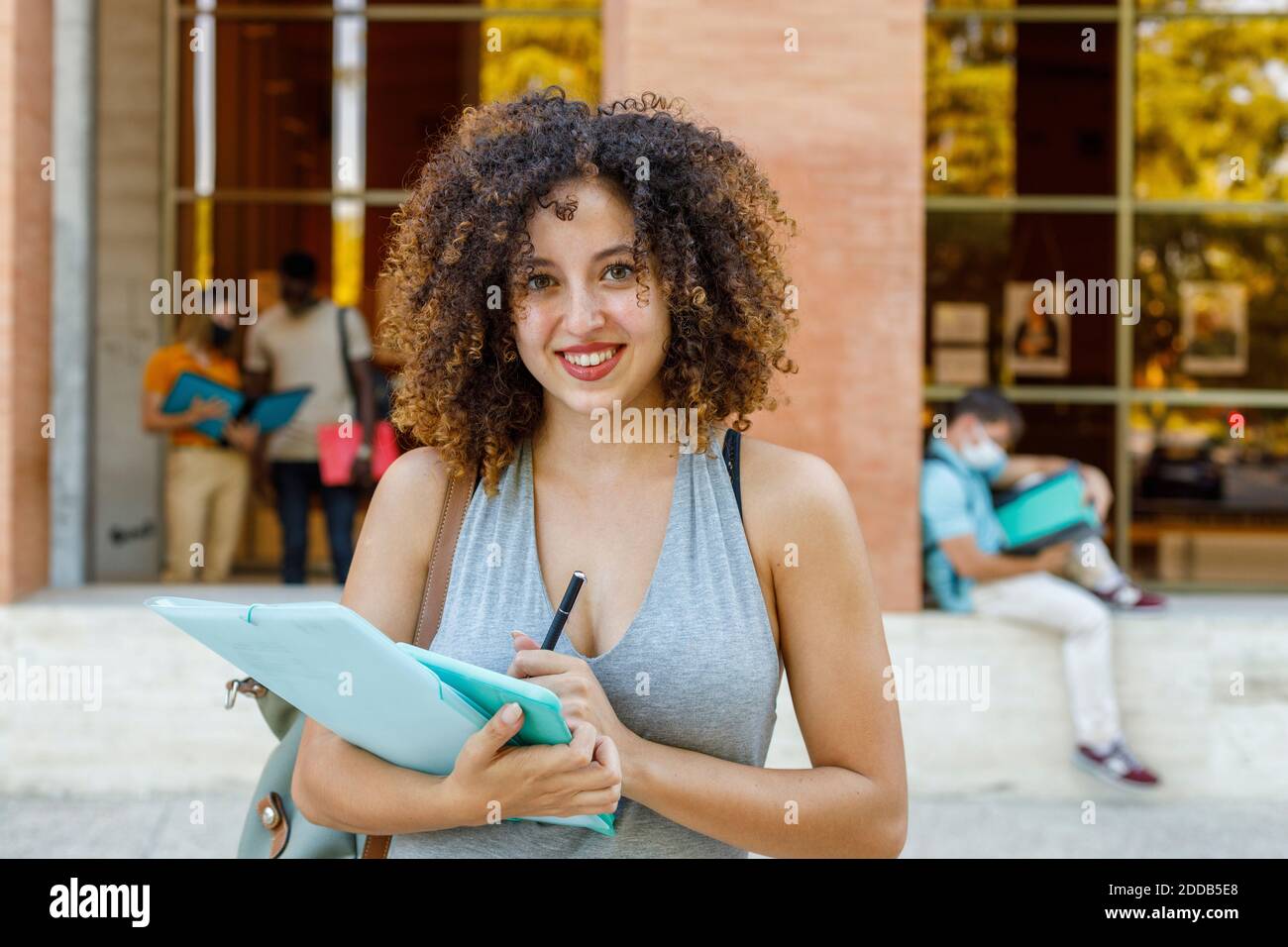 Young smiling woman with documents standing in university campus Stock ...
