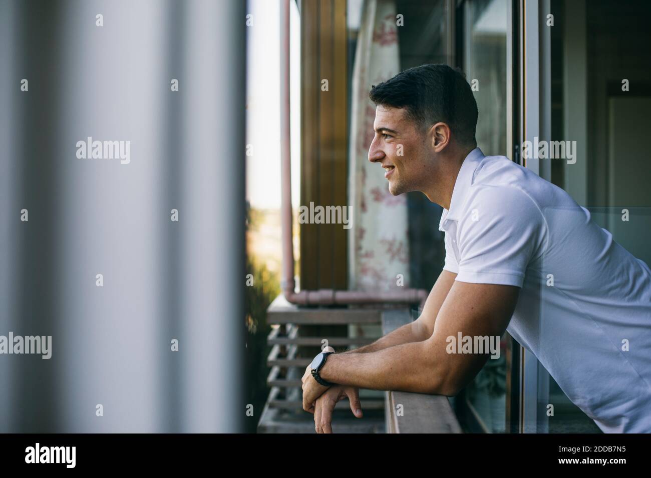 Smiling man looking away while leaning on balcony railing Stock Photo ...