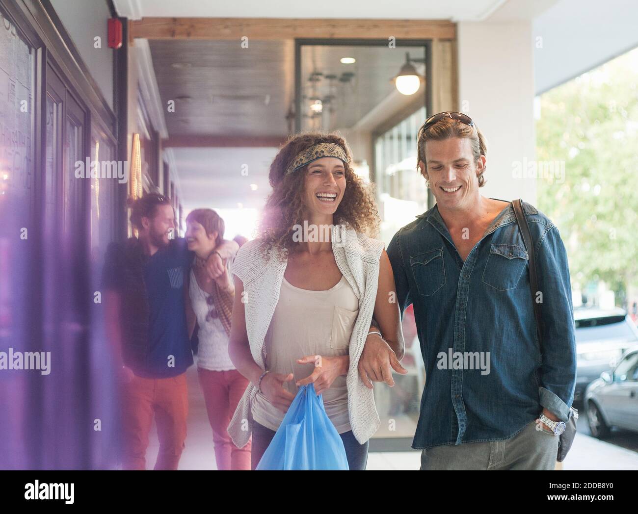 Friends laughing while walking on street in city Stock Photo - Alamy