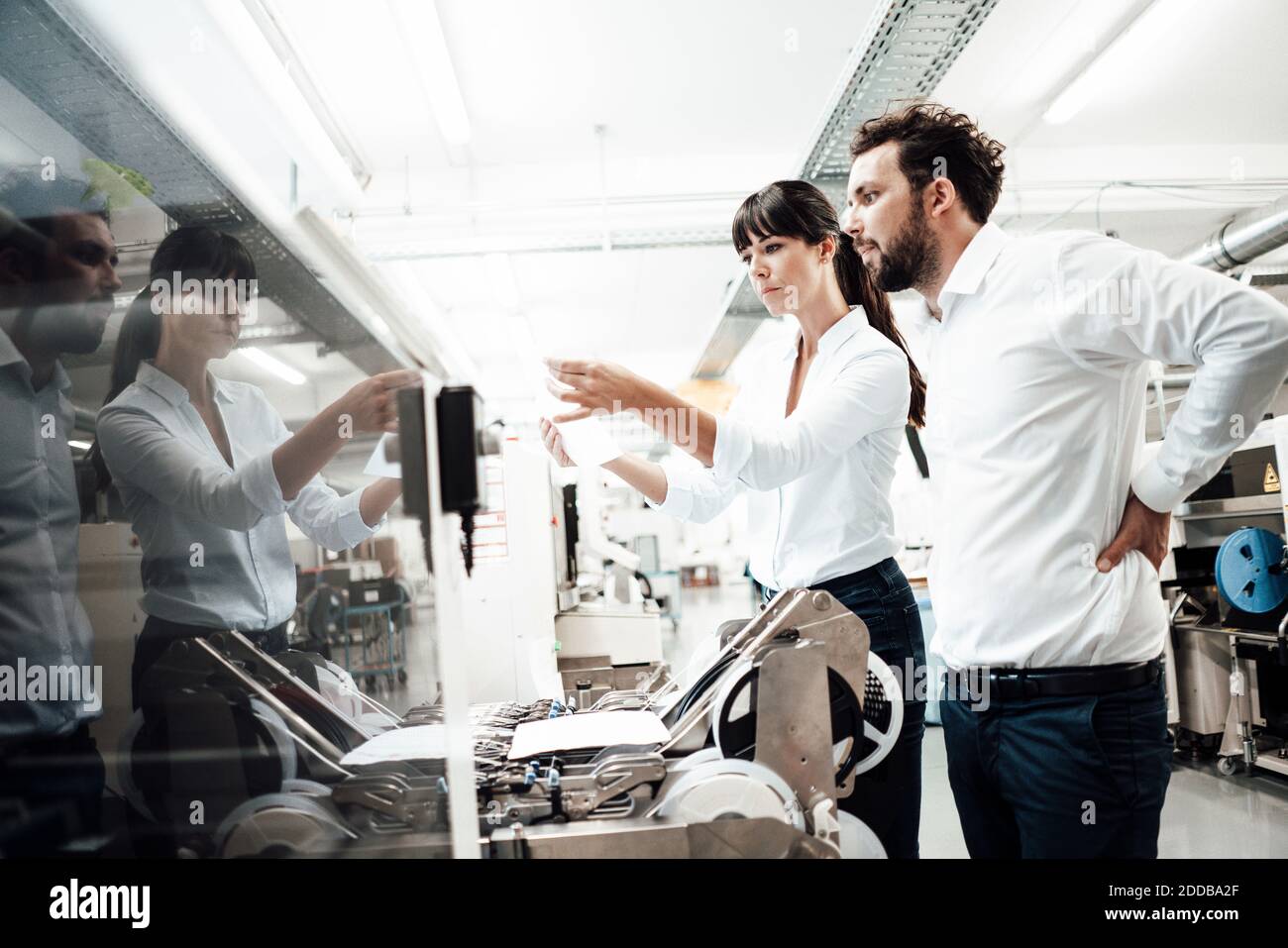 Male and female engineers looking at paper while investigating ...