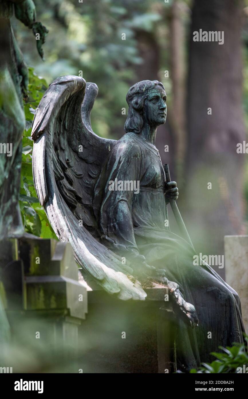 Weathered statue of angel sitting at edge of tomb in cemetery Stock ...