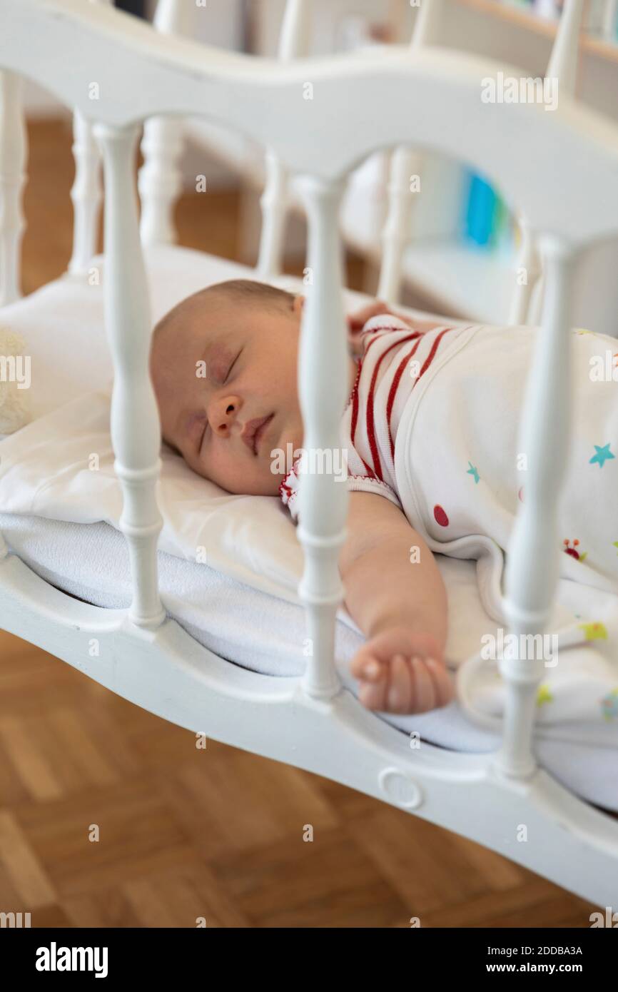 Baby girl lying down in crib at home Stock Photo - Alamy