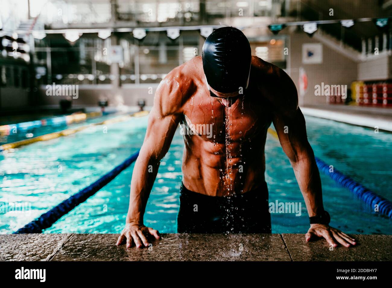 Wet young male swimmer getting out of swimming pool Stock Photo - Alamy