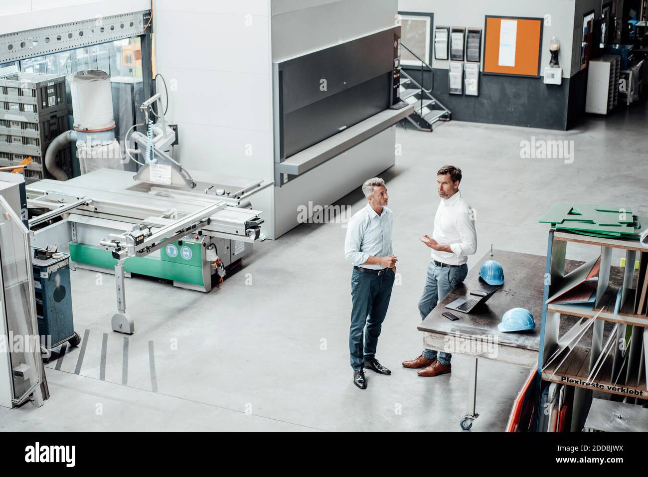 Mature businessmen discussing while standing in manufacturing industry ...