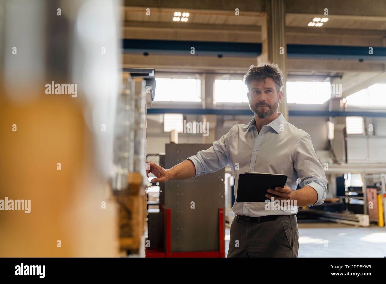 Male inspector using digital tablet while inspecting material in ...