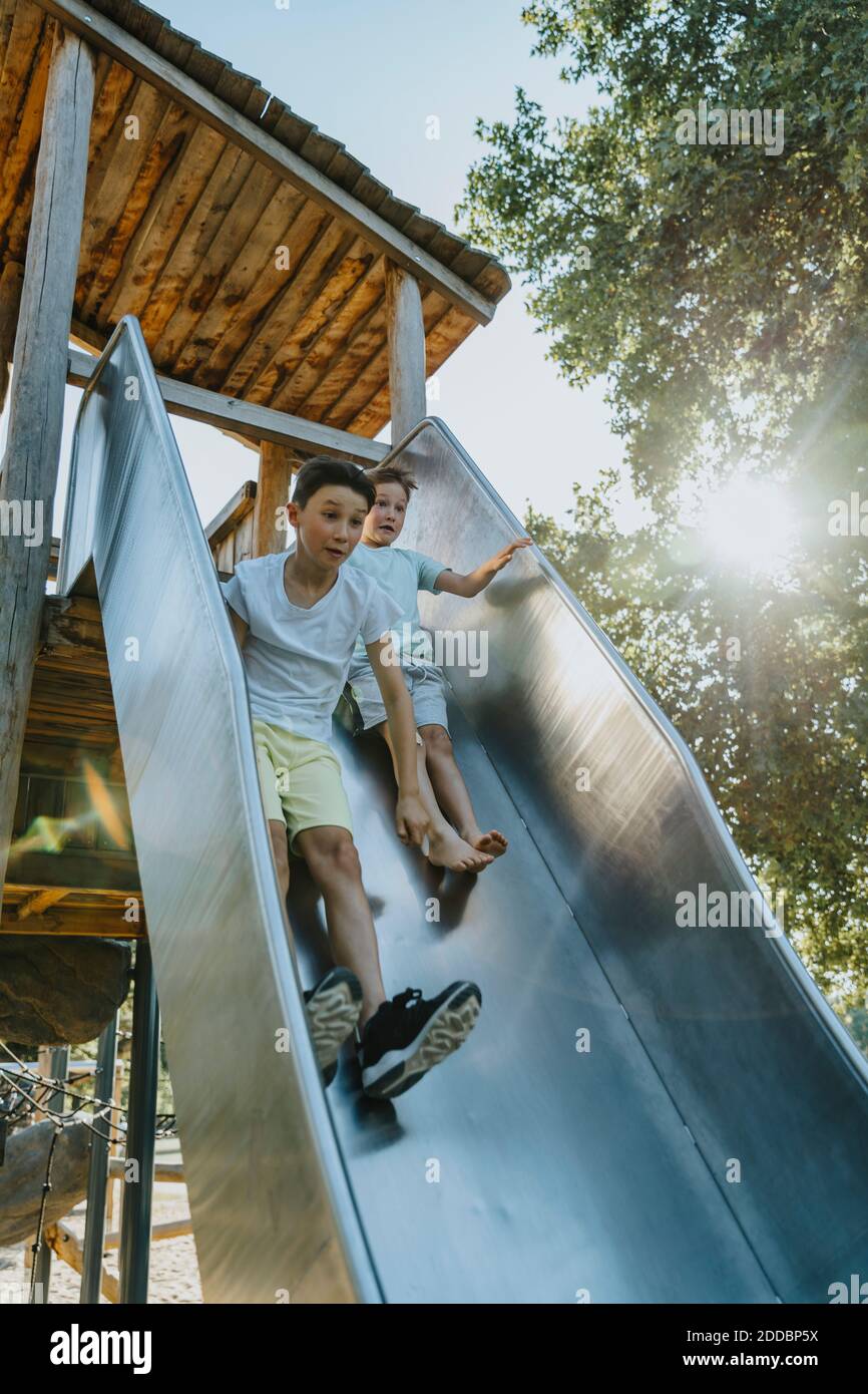 Brothers sliding on slide in public park on sunny day Stock Photo - Alamy