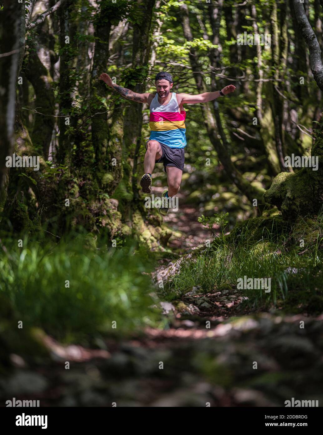 Man with arms outstretched running on mountain trail at forest Stock ...