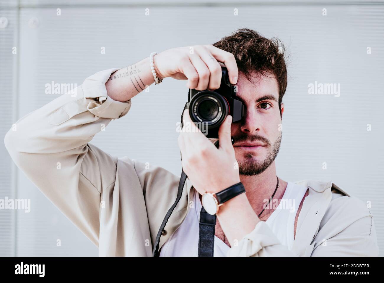Confident man taking photograph through camera while standing against ...
