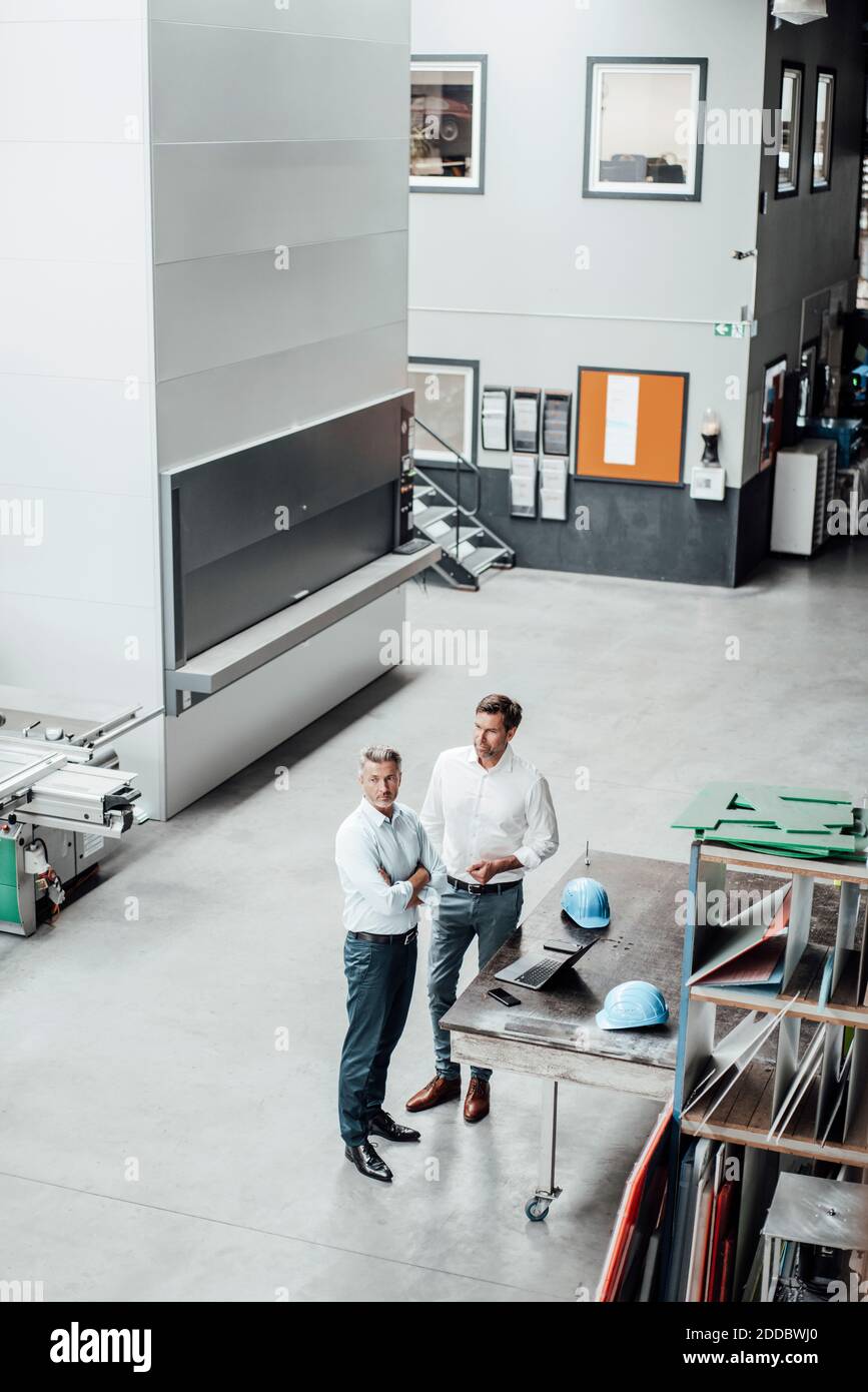 Male colleagues standing by table in manufacturing industry Stock Photo ...