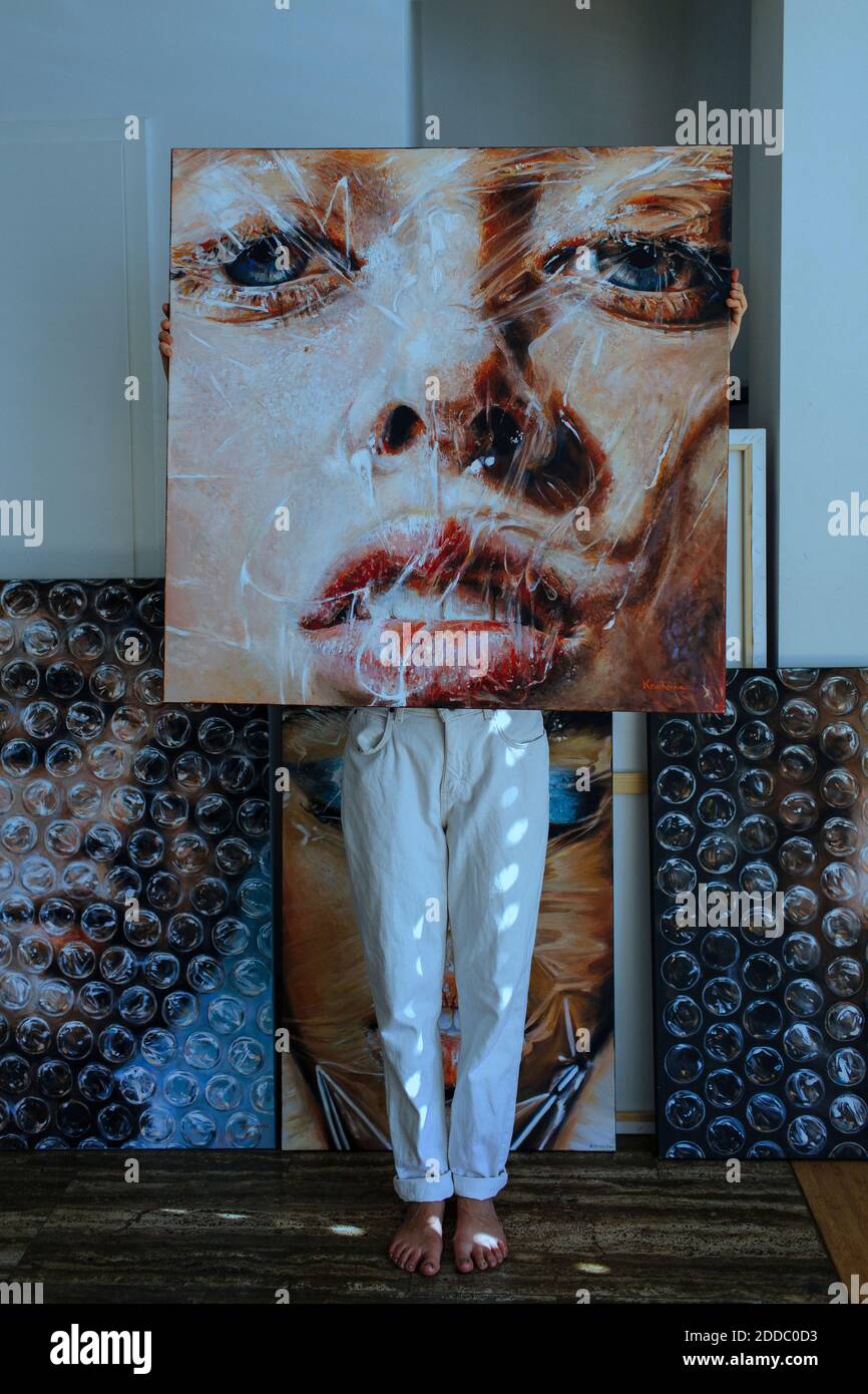 Female artist standing behind painting against wall in art studio Stock ...