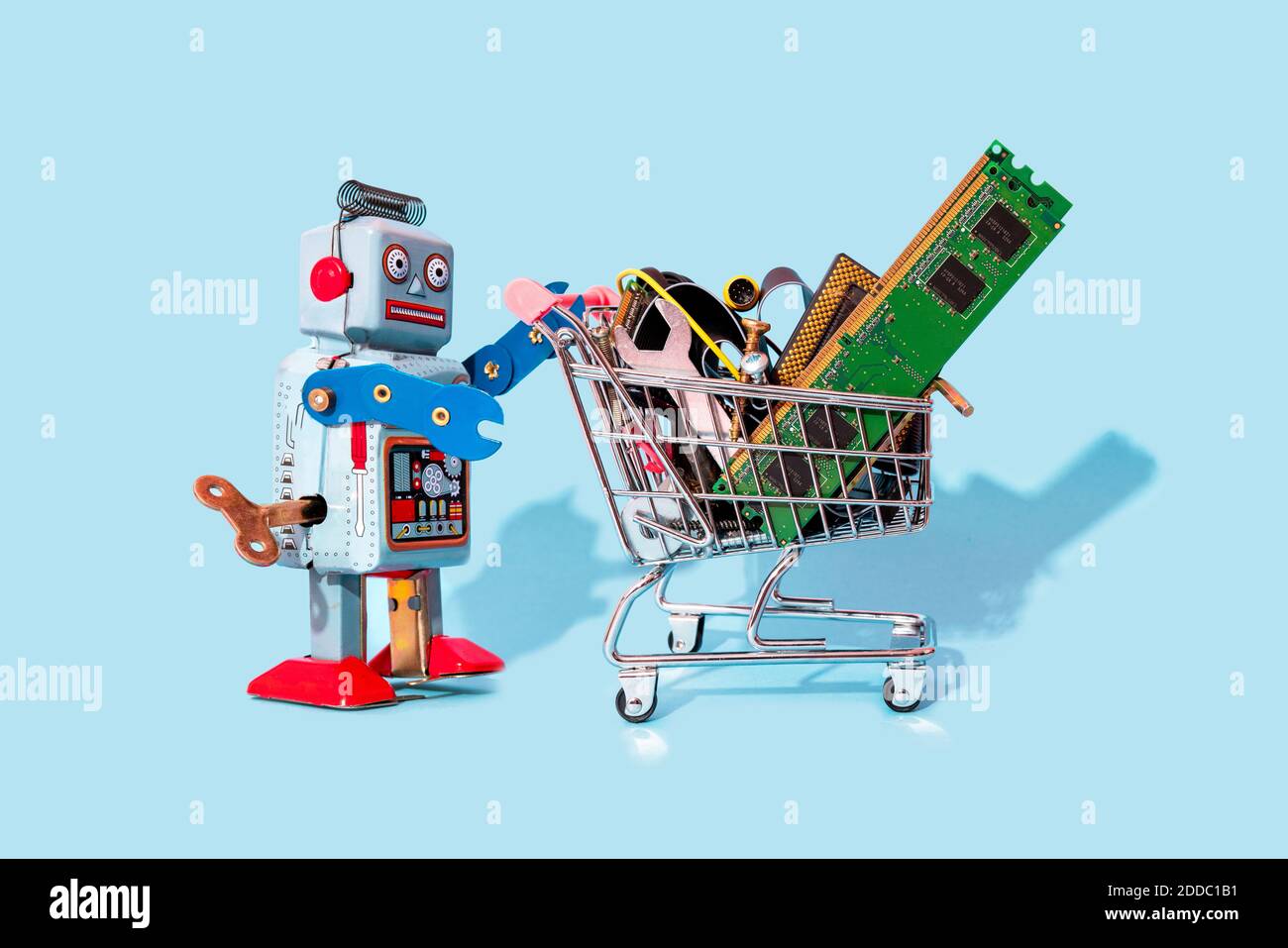 Studio shot of vintage robot toy pushing miniature shopping cart filled ...