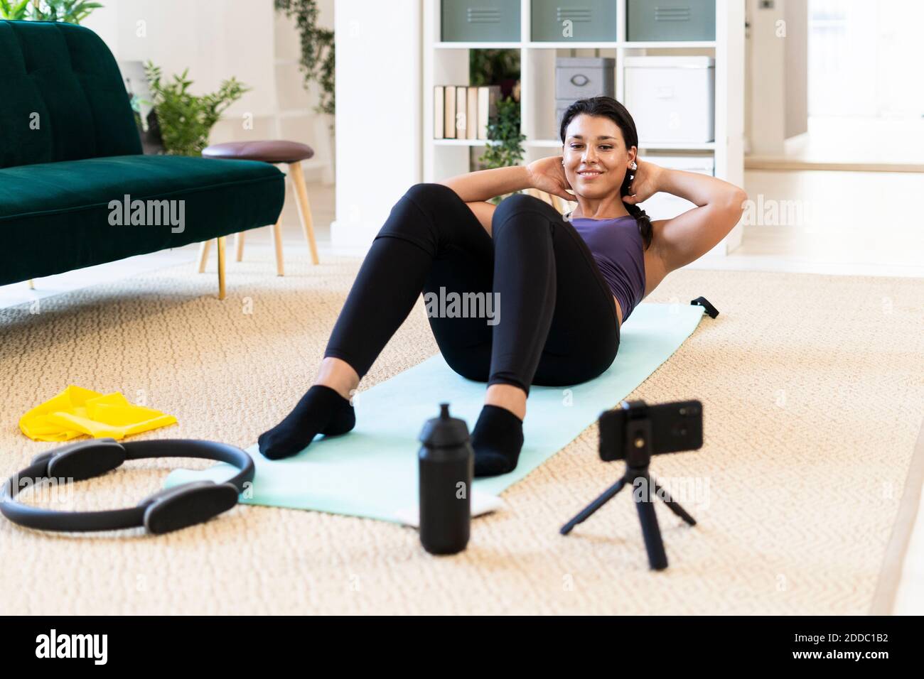 Young woman doing crunches with hands behind head while lying down at ...