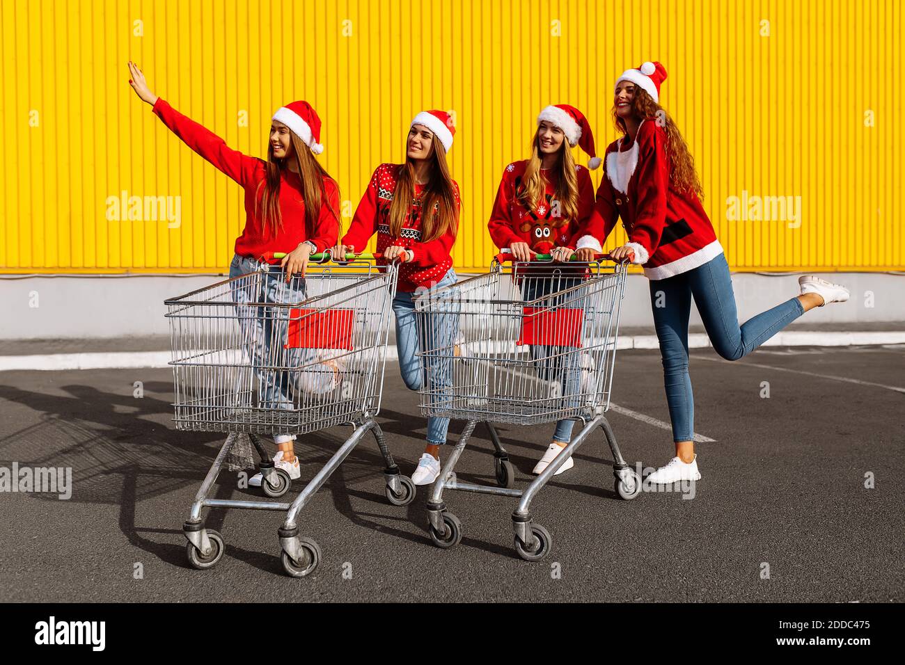 Group of four young women in christmas sweaters and santa claus hats ...