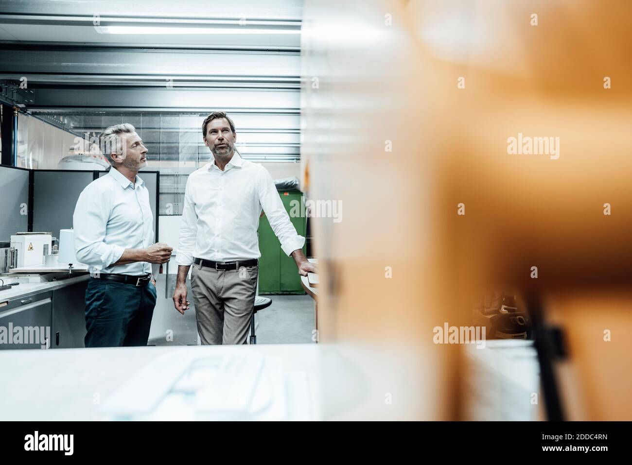 Male engineers discussing while standing in factory Stock Photo - Alamy