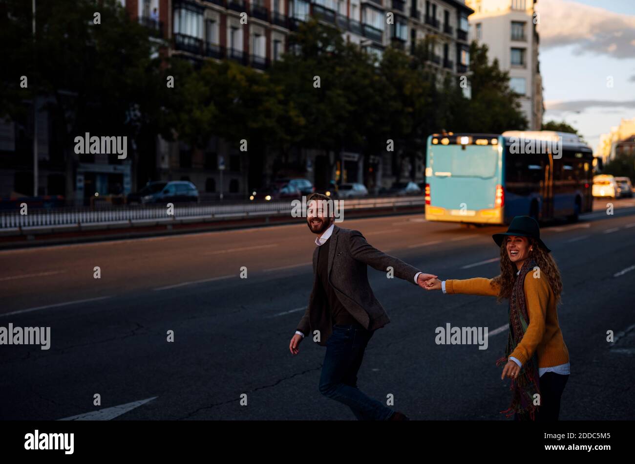 Couple holding hands while crossing road in city Stock Photo - Alamy