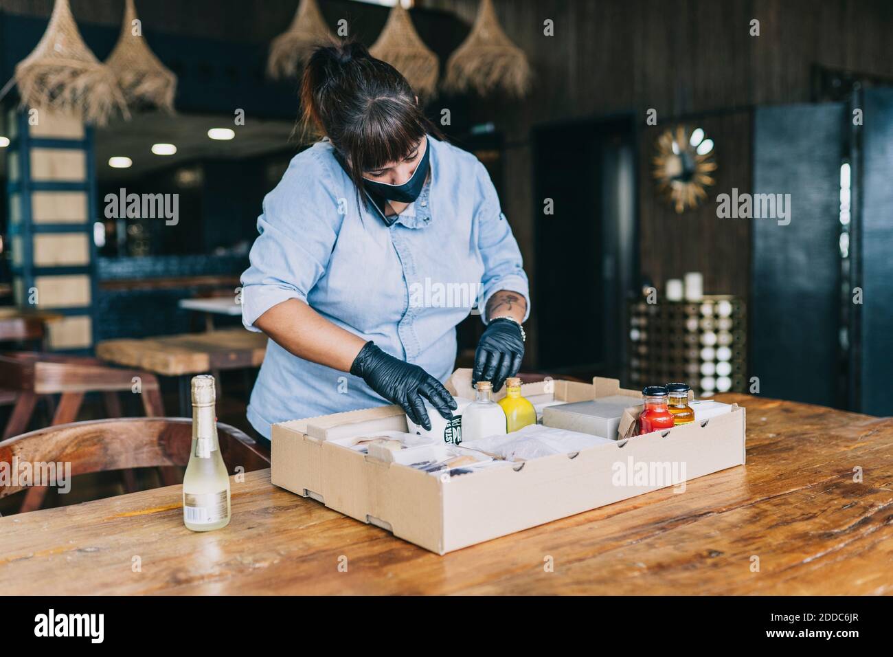 Female chef talking on phone while arranging take out box at kitchen ...