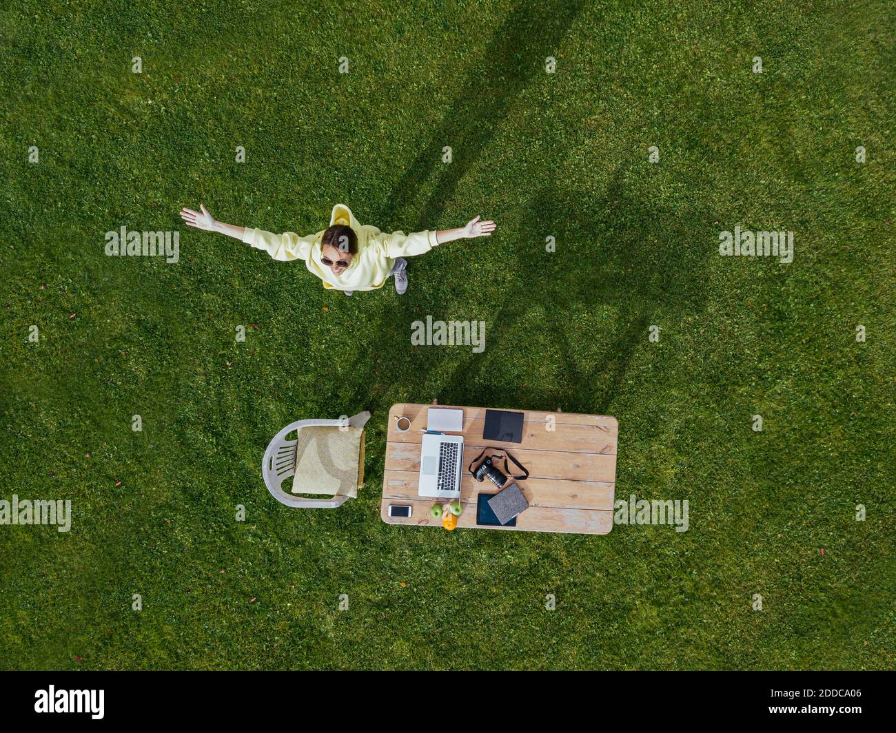 Aerial view of woman standing with raised arms in front of coffee table ...