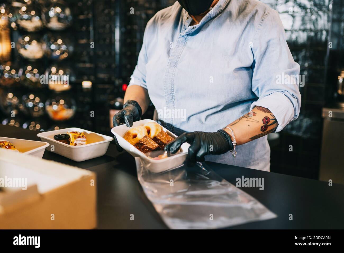 Midsection of female chef putting take out food container in plastic ...