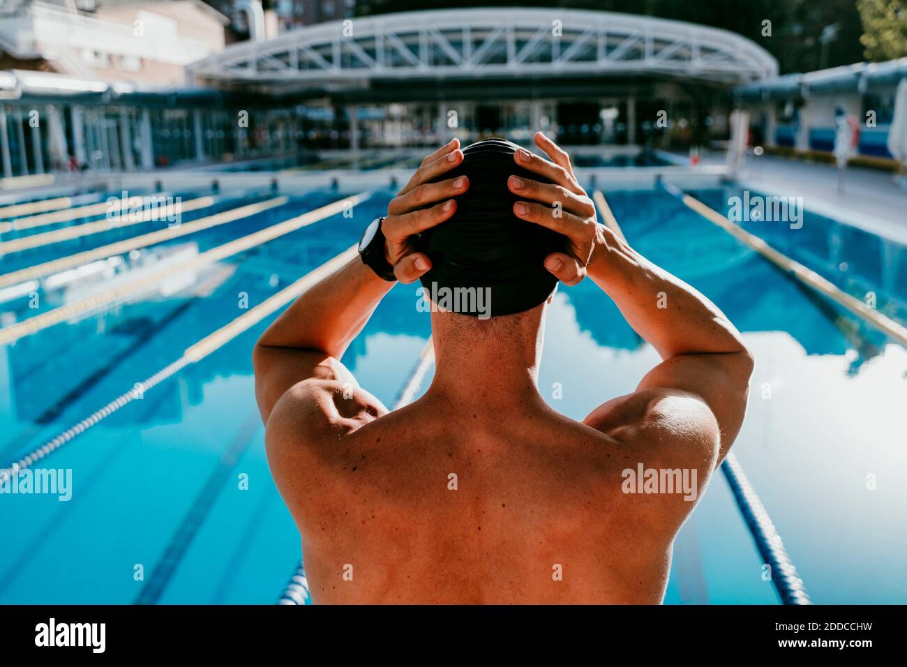 Man adjusting swimming cap before diving into water during sunny day ...