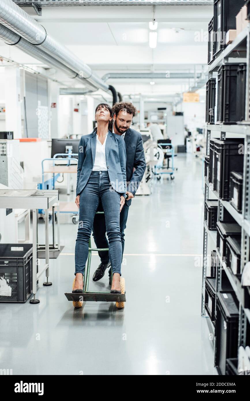 Businessman pushing female robot on cart at bright industry Stock Photo ...