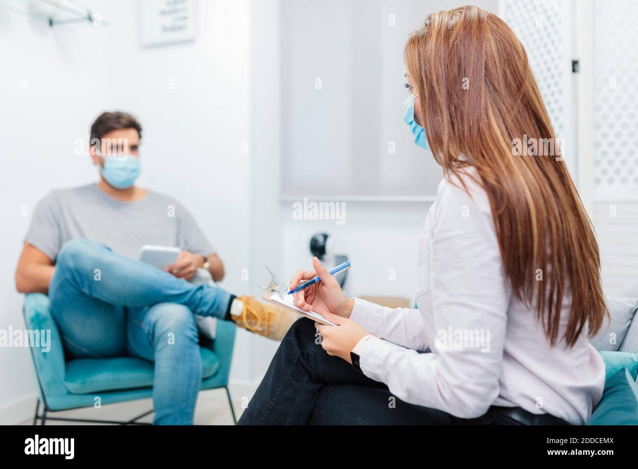 Doctor writing in notepad while listening to patient problem at office ...