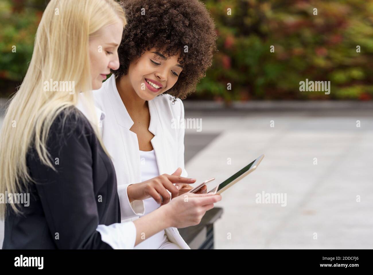 Two multiethnic female entrepreneurs sitting hi-res stock photography ...
