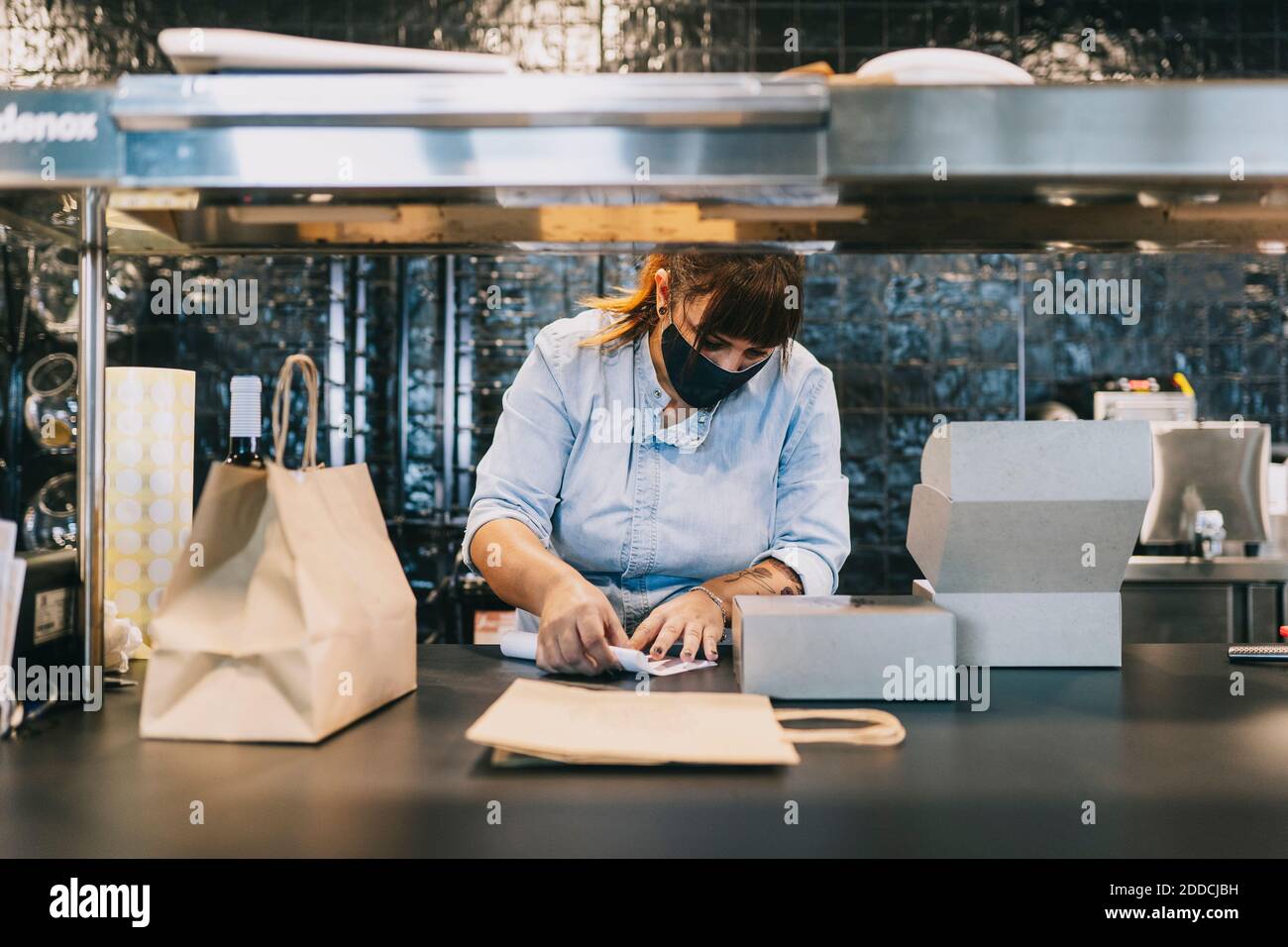 Female chef holding paper by take out containers at restaurant kitchen ...