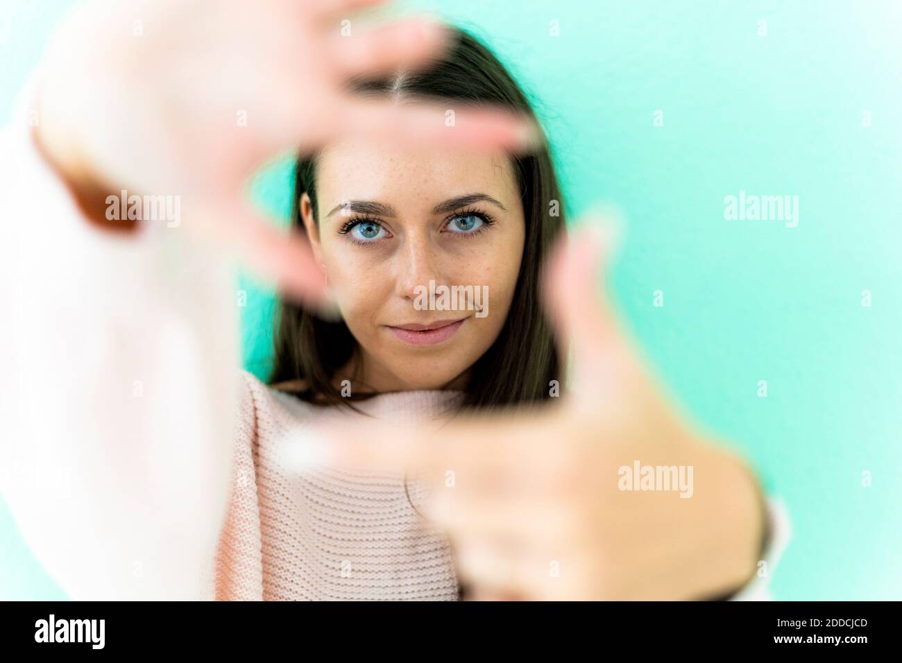 Beautiful young woman making finger frame against green wall Stock ...