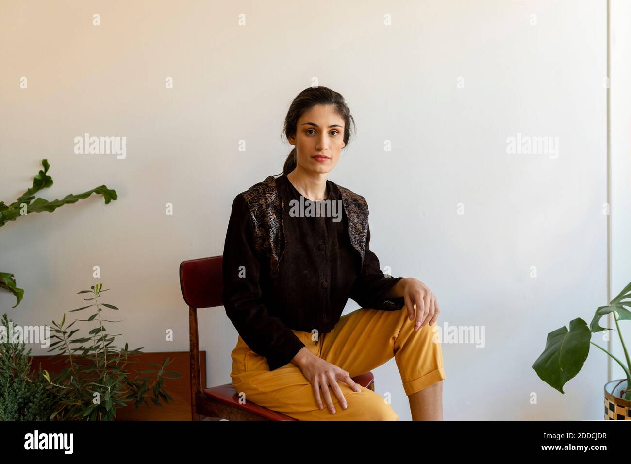 Beautiful female model sitting on chair at home Stock Photo - Alamy