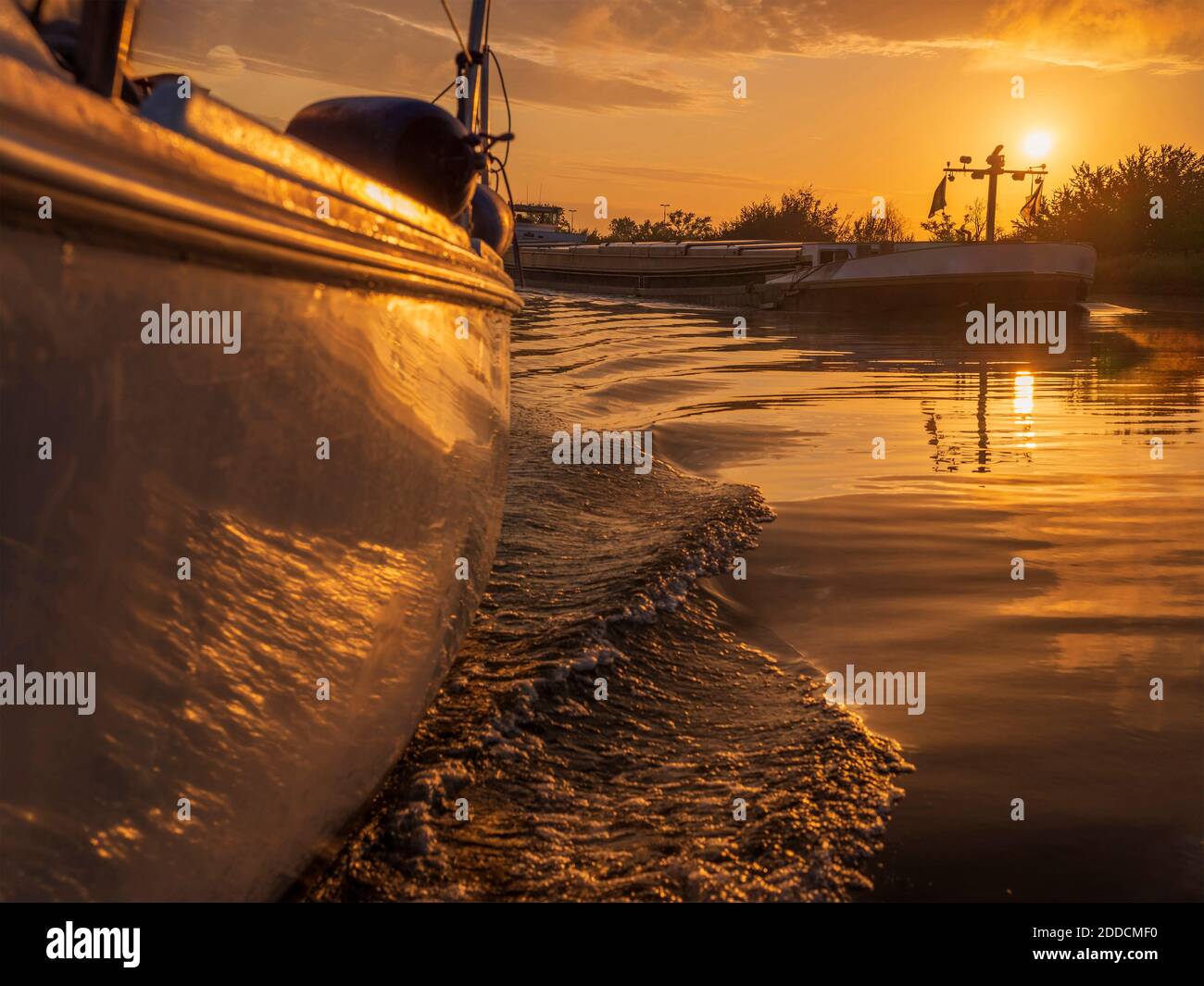 Boat sailing along Juliana Canal at sunrise with barge trailing behind ...