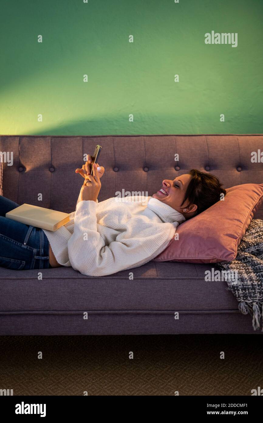 Woman lying on sofa texting hi-res stock photography and images - Alamy