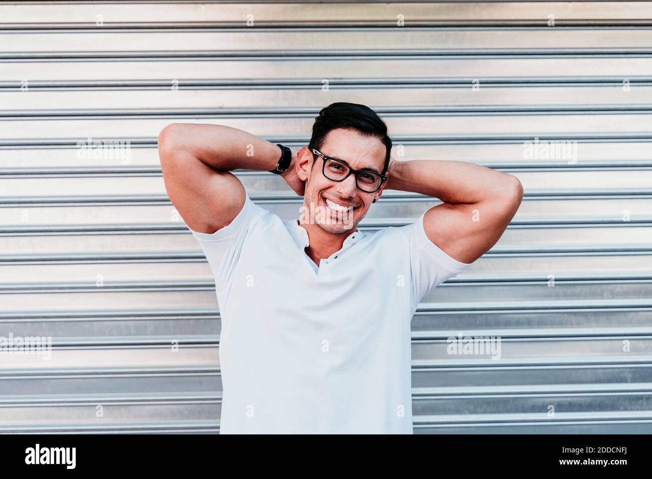 Smiling male with hand in hair against shutter Stock Photo - Alamy