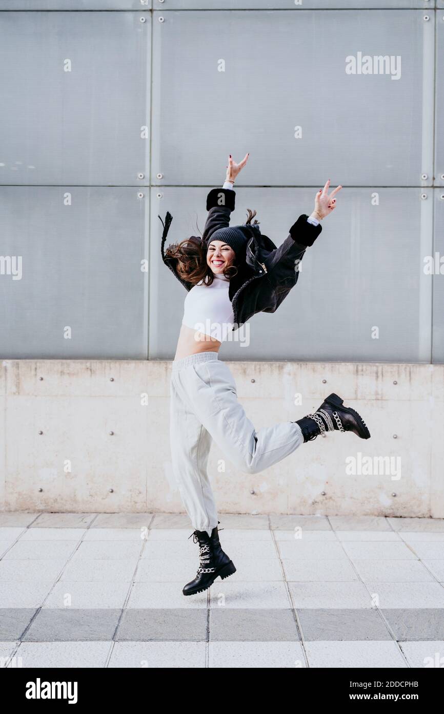 Happy female in jacket dancing against wall Stock Photo - Alamy