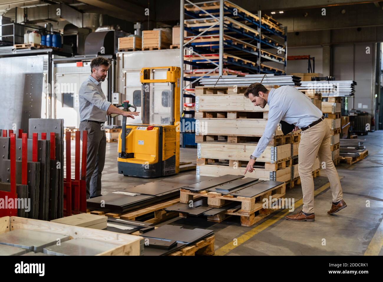 Business people inspecting metal material while standing at warehouse ...