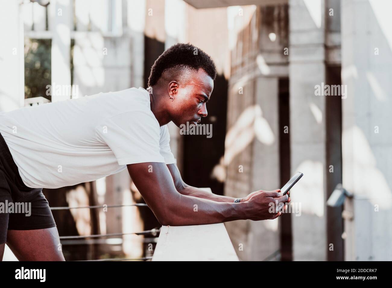 Sportsman leaning on railing using smart phone while standing Stock ...
