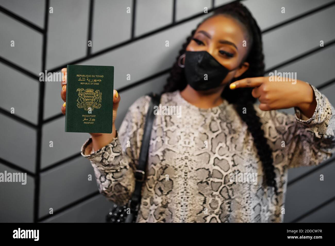 African woman wearing black face mask show Chad passport in hand ...