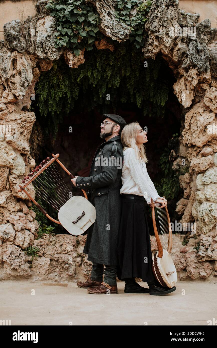 Male and female with lyra musical instrument against built structure ...