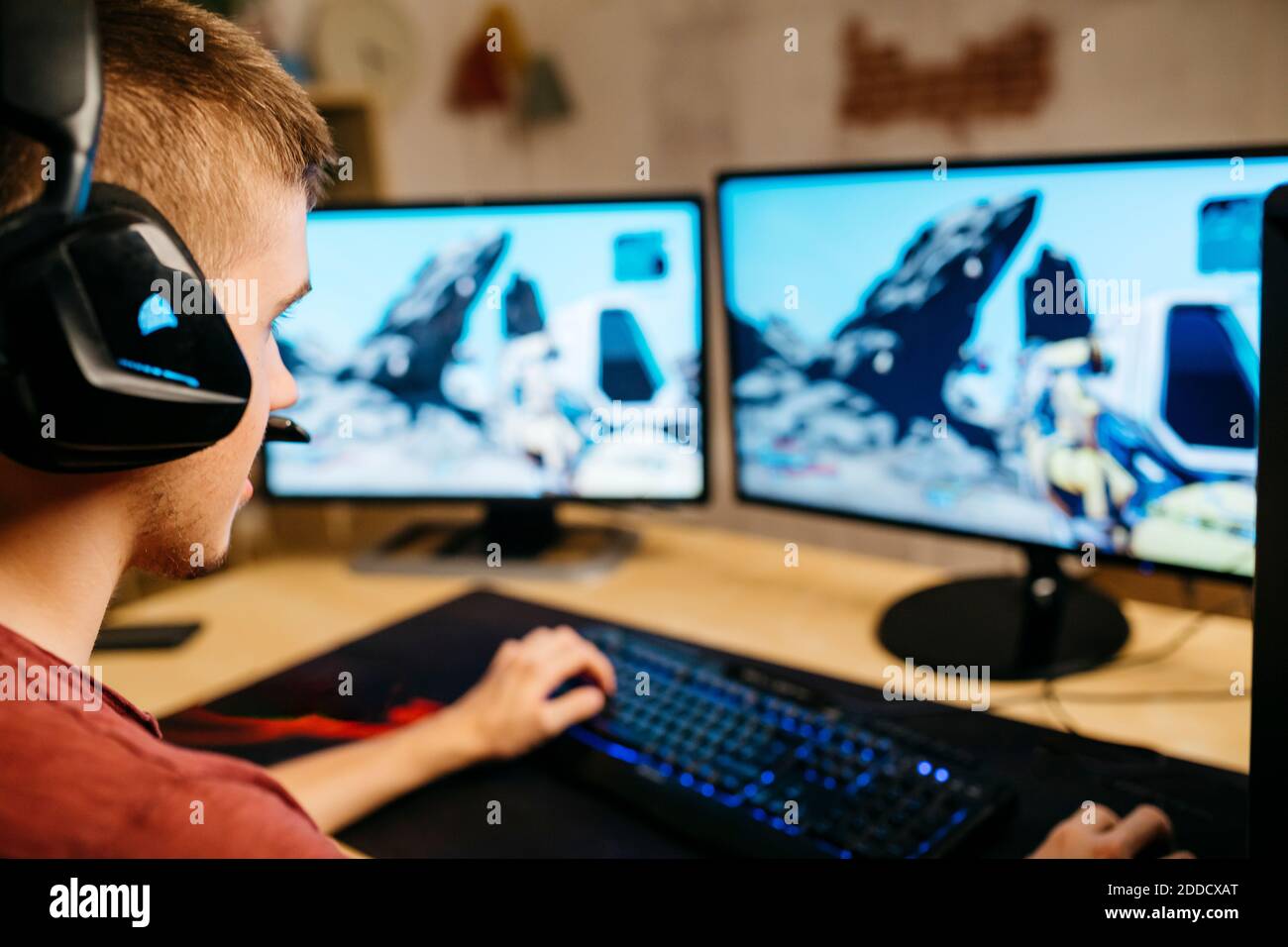 Young man playing video games with computer at desk Stock Photo - Alamy