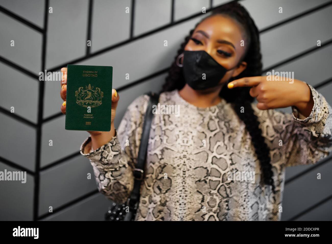 African woman wearing black face mask show Lesotho passport in hand ...