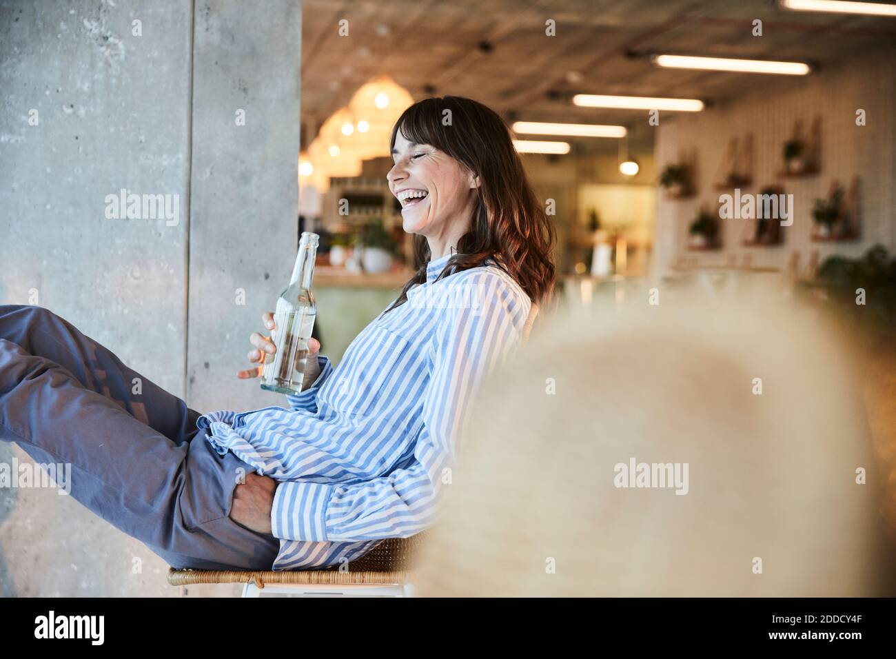 Mature woman laughing while drinking beer sitting at home Stock Photo ...